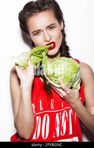 Daring funny girl with braids and red lips, emotional eating cabbage ...
