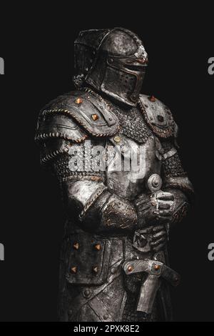 Statue of medieval knight in metal armor with a sword, isolated on dark ...