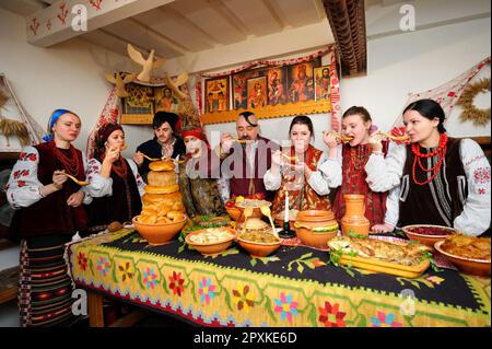 Family in Ukrainian native costumes gathered behind table to prepare ...