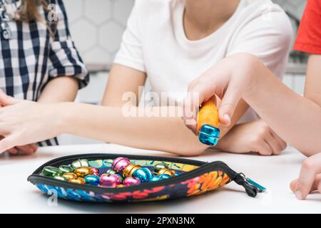 Side view of group of preteen children sitting at white table, catching ...