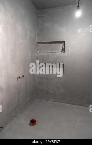 Empty room in a house under construction, plastered walls, screed on ...