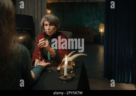 Mature witch using crystal pendulum to predict future for client Stock ...