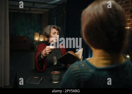 Gypsy reading spell for client using witchcraft book and magic pendulum ...