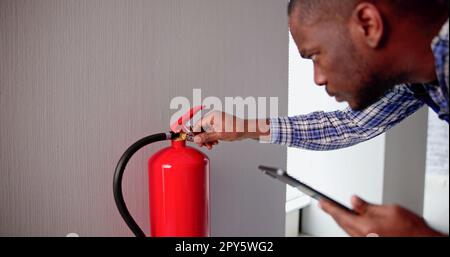 Male Professional Checking A Fire Extinguisher. Security Inspection ...