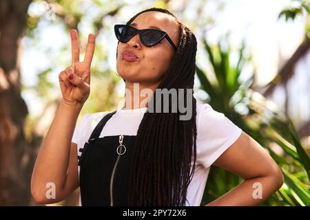 Peace everyone. Trendy young woman giving a peace gesture against a ...