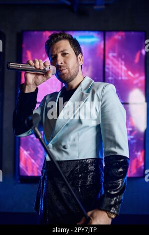 Male singer holding microphone standing and performing on stage Stock ...