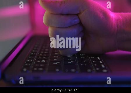 Human fist bump on the keyboard of laptop. Neon pink blue light ...