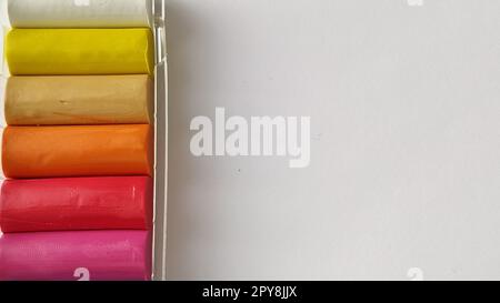 Multi-colored plasticine in plastic packaging on a white background ...