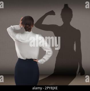 Businesswoman and shadow of strong muscular lady behind her on light ...
