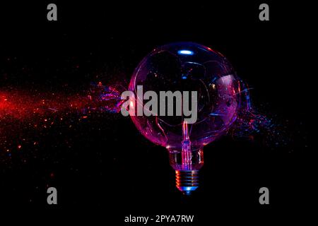 large filament bulb breaks and creates fragments. black background ...