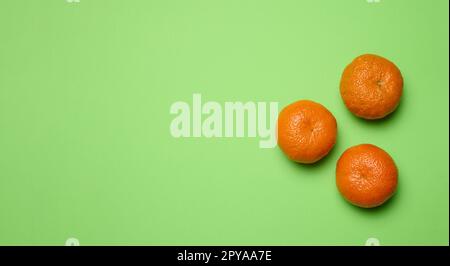 Three ripe mandarins on green background, top view. Ripe fruit Stock ...