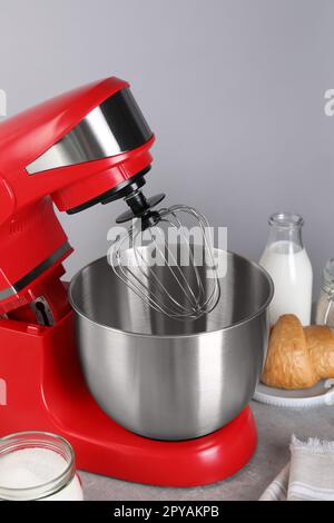 Modern red stand mixer, croissant and ingredients on gray marble table ...
