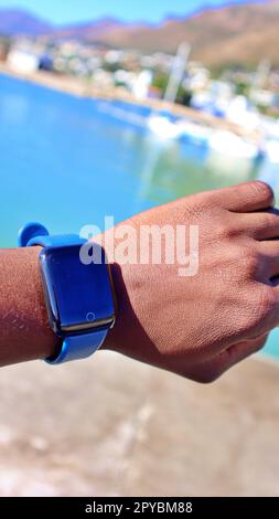 Closeup arm wrist wearing smart watch, screen lit up, using other hand ...