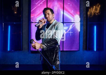 Male singer holding microphone standing and performing on stage Stock ...