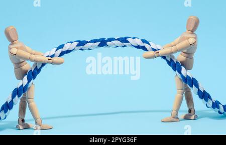 Two wooden mannequins are pulling a rope, concept of a strong leader in ...