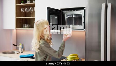 Woman Using Microwave Oven For Heating Food Stock Photo - Alamy