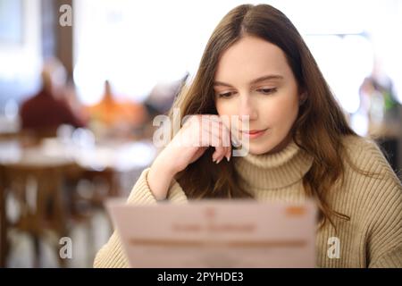 Happy woman reading menu card in a bar Stock Photo - Alamy