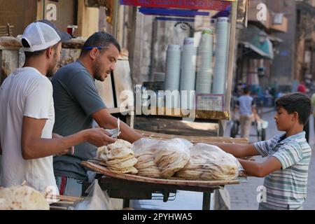 CAIRO, EGYPT. A man selling flatbread ('aish shamsi) from the bonnet of ...