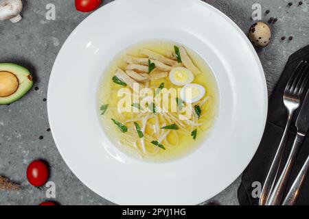 Low-fat chicken broth with a half cooked egg and parsley in a glass ...
