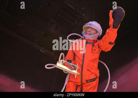 A Russian cosmonaut in an orange space suit floats above a capsule. A ...