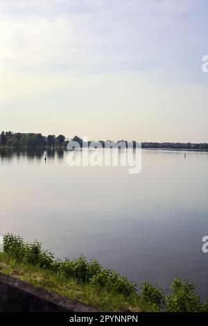 Lake and town by the shore casted in the water at sunset seen from afar ...
