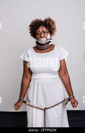 Portrait of sad woman trapped with old rusty chains and mask on her ...