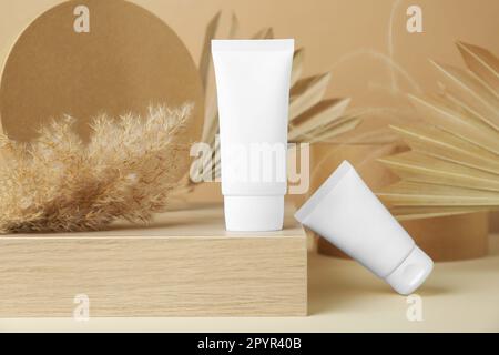Composition with tubes of hand cream on beige background, space for ...
