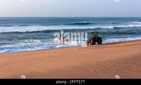 Fishing boat entry into surf ocean waves off beach sand by tractor ...