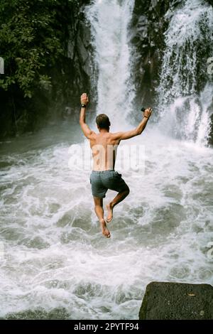 A man jumps from a waterfall. Bali Stock Photo - Alamy