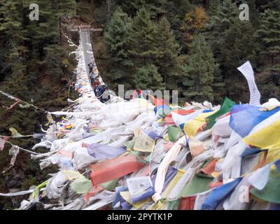 Buddhist prayer flags tied to a metallic hanging bridge called "Hillary ...