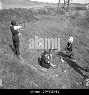 Three women are practicing shotgun shooting. While one of them is ...