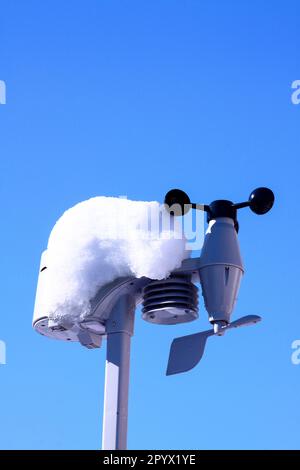 Home weather station outdoor sensors covered in snow against a blue ...