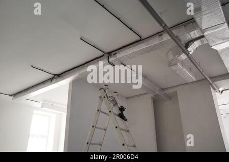 Conduits with cables and ventilation system on white ceiling, low angle ...