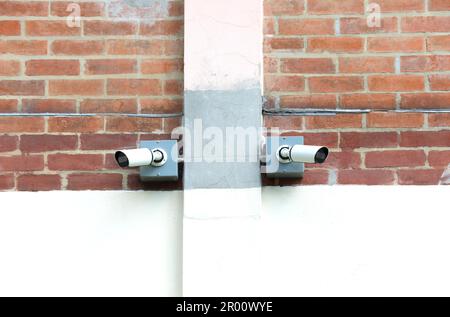 Two surveillance cameras installed on pole near warehouse with brick ...