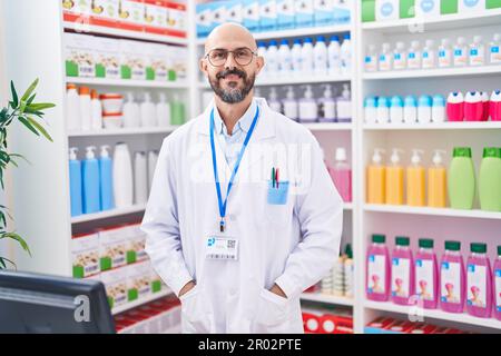 Young bald man pharmacist smiling confident holding medication on ...