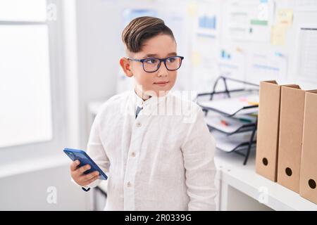Adorable hispanic boy business worker standing with serious expression ...