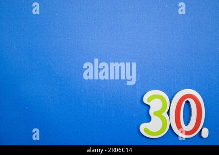 The number 30, placed on a blue background, photographed from above ...