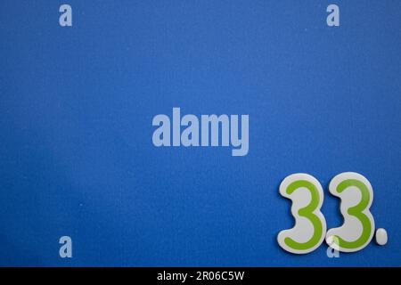 The number 33, placed on a blue background, photographed from above ...