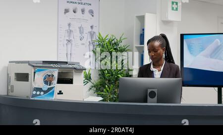 Woman nurse answering landline phone call at reception desk in ...