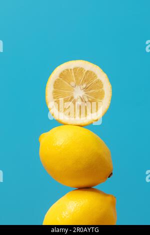 A pyramid of juicy yellow lemons on a blue background. Creative concept ...