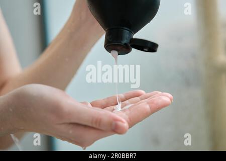 Pouring shampoo from bottle on female hand in bathroom. Hygiene concept ...