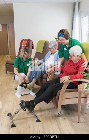 Nurse helping senior women doing exercise on mini foot pedal in rest ...