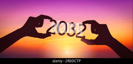 2032 - human hands holding black silhouette year number, gradient ...