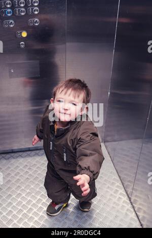 Happy baby rides in the elevator of an apartment building with buttons ...