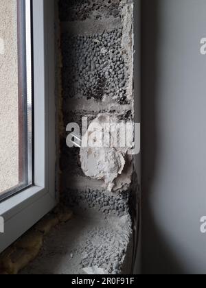 Old mounting foam between a plastic window and a brick wall close-up ...