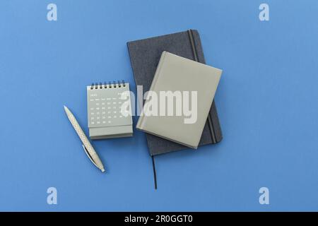 Flip paper calendar for August with notebooks and pen on blue ...