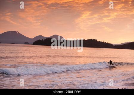 ALASKA, Sitka, a surfer catches waves created by the tidal shift ...