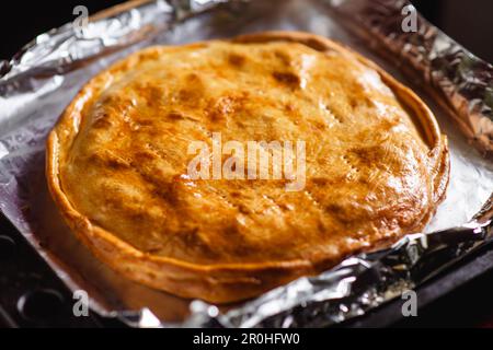 Cooked closed pie. Baked round cake on a baking sheet. Top view Stock ...