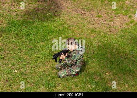 Boy weared in camouflage playing laser tag in special forest playground ...