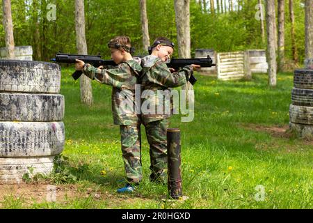 Two boys weared in camouflage playing laser tag in special forest ...